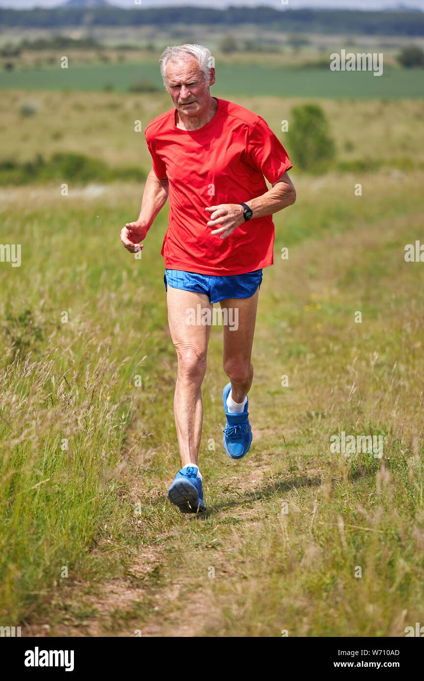 Senior runner running on the meadow road Stock Photo - Alamy