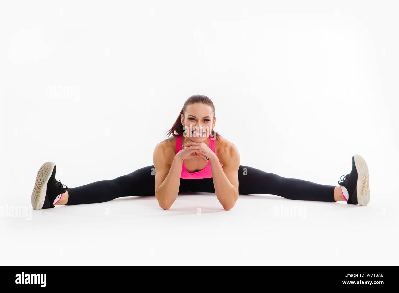 Young smiling girl in sportswear sitting on splits and looking at ...