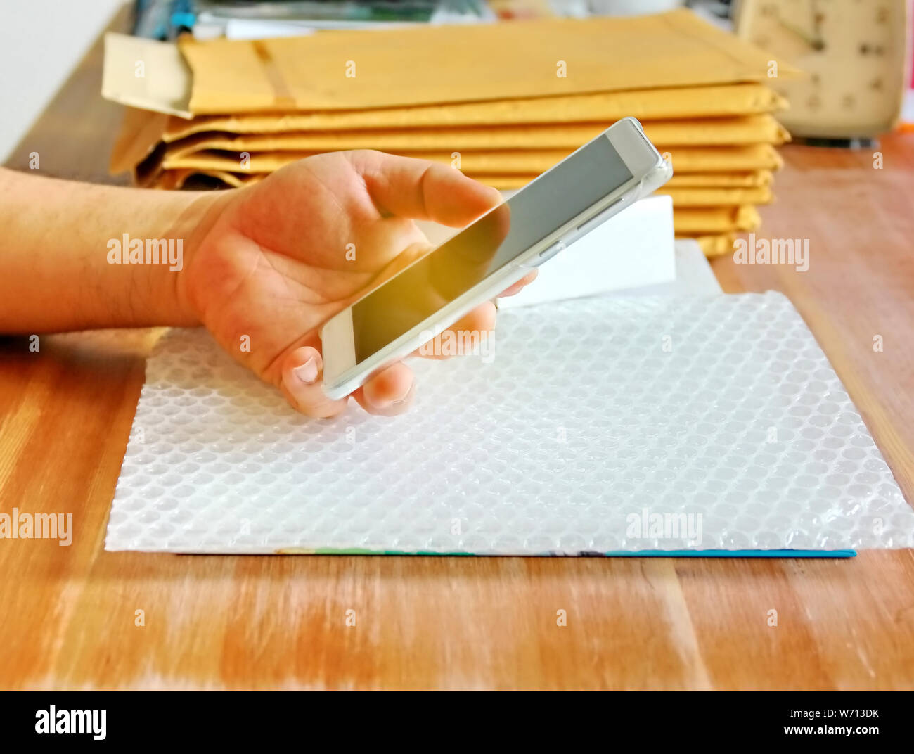 hand using smartphone in parcel delivery shop. man calling to customer ...