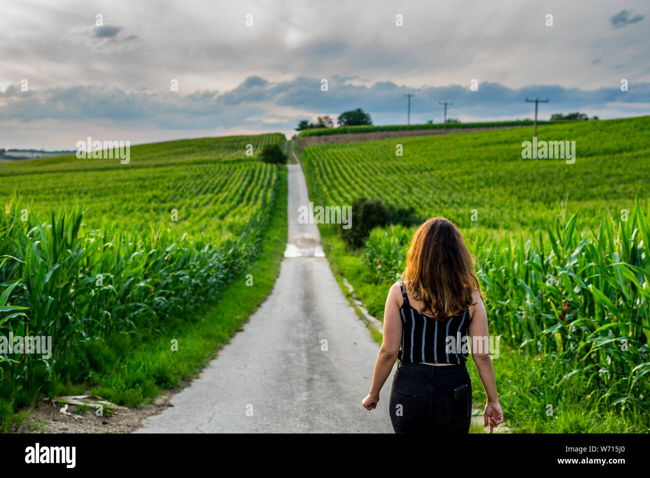 Woman hiking on long path on bavarian field with cloudy sky Stock Photo ...