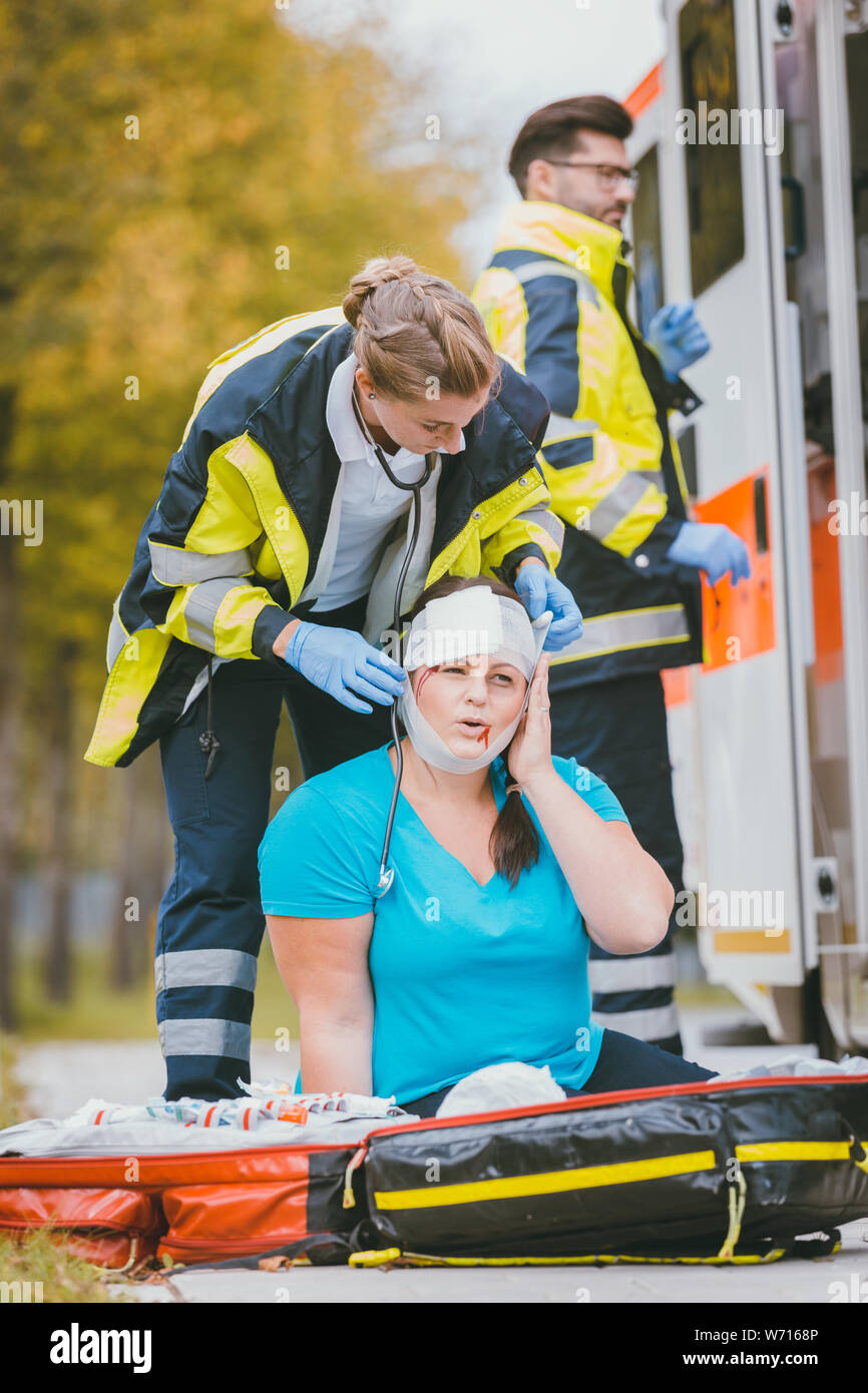 Emergency medics dressing head wound of injured woman Stock Photo - Alamy