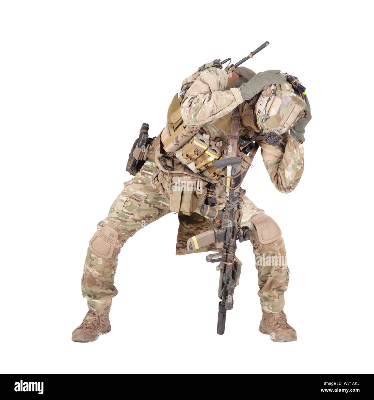 Armed infantryman in camo uniform and helmet embracing head with hands ...