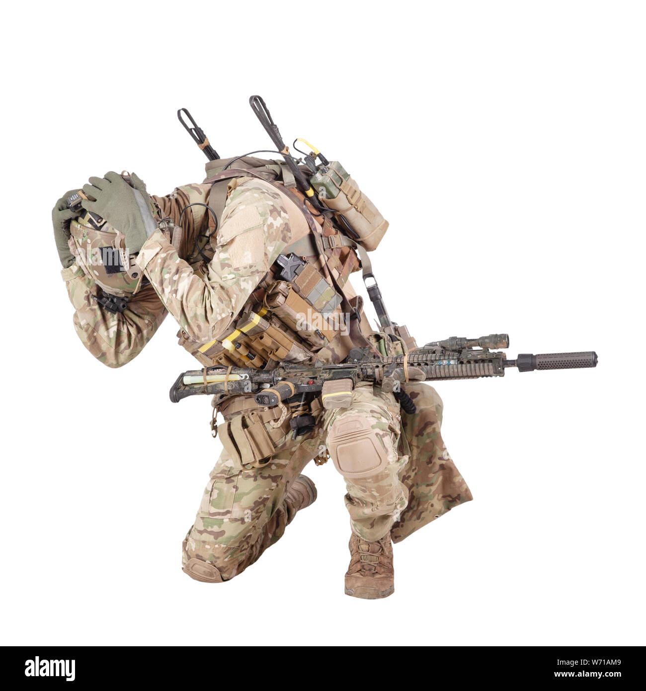 Armed infantryman in camo uniform and helmet embracing head with hands, covering himself from ...