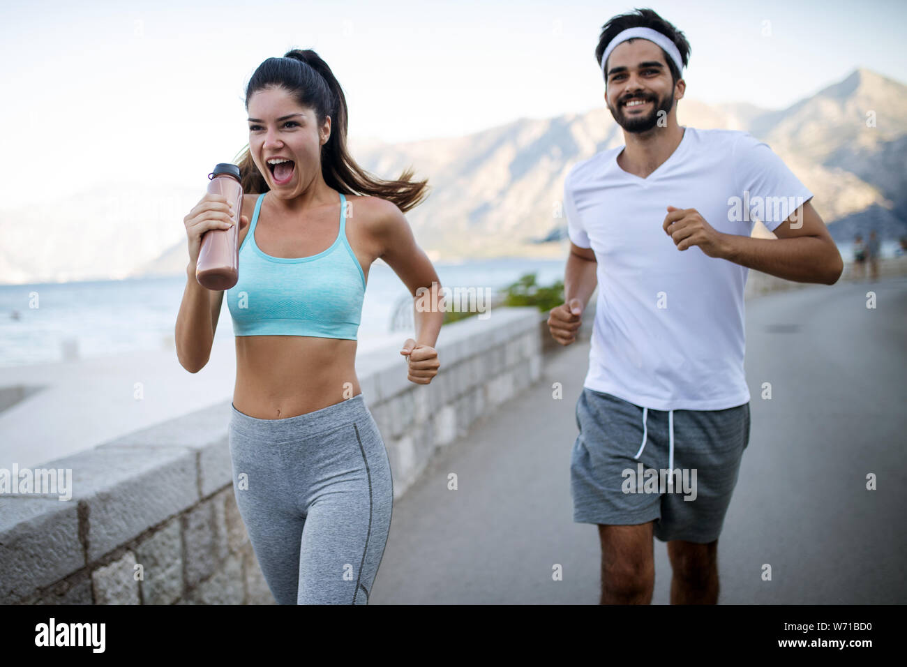Happy fit people couple jogging and running outdoors Stock Photo - Alamy