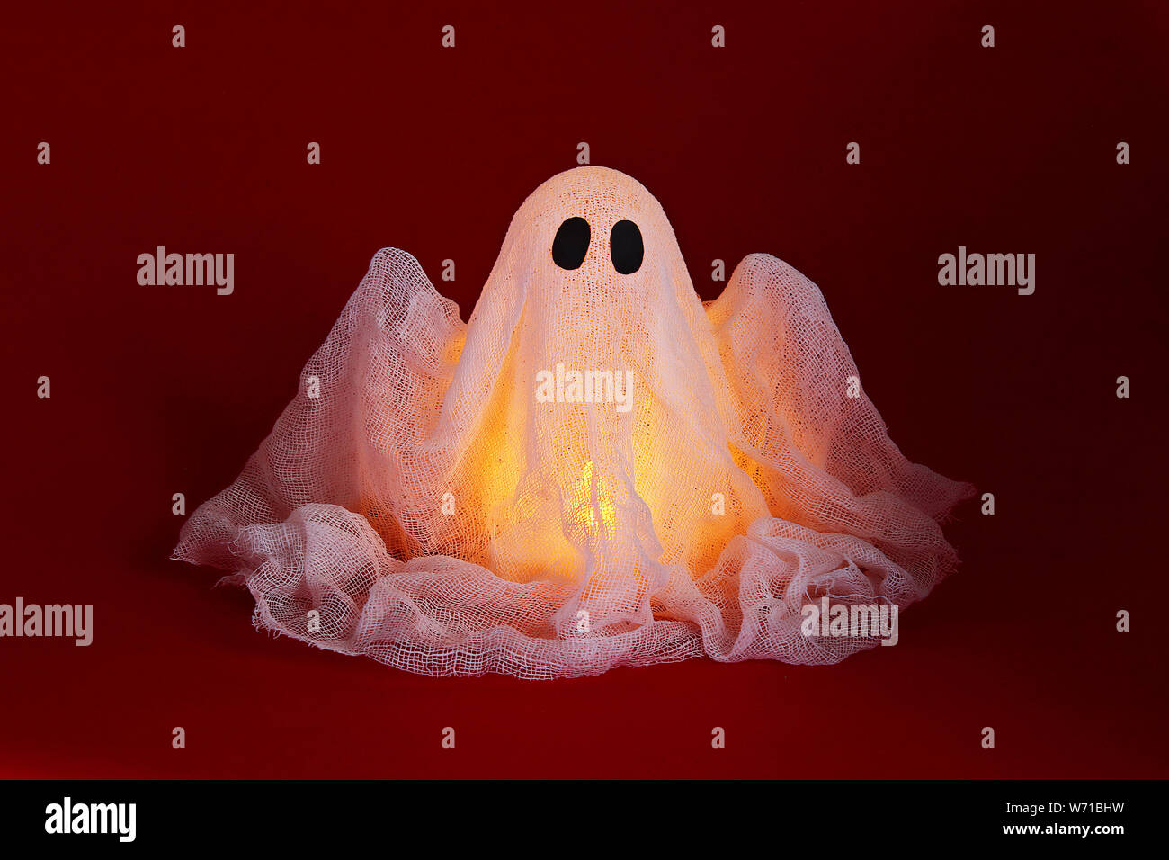 Halloween ghost of starch and gauze on orange background. Gift idea ...
