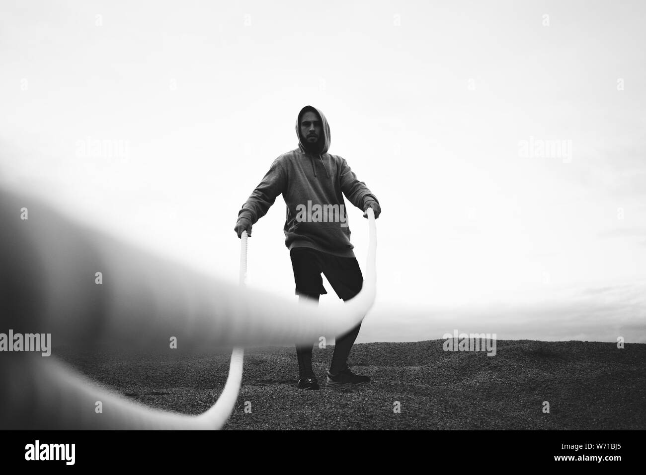 Young athlete training body with two battle ropes on outdoor. Strong ...