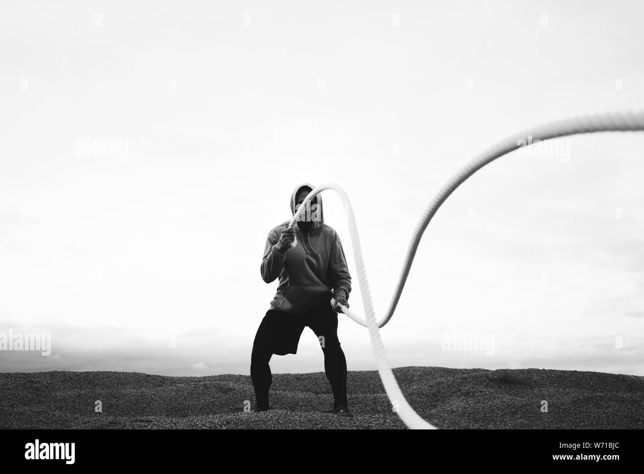 Young athlete training body with two battle ropes on outdoor. Strong ...