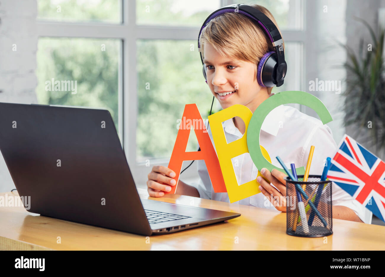 Young schoolboy learning english using online course with laptop ...