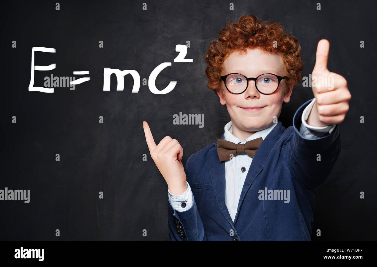 Smiling little boy with ginger hair pointing at science formula on ...