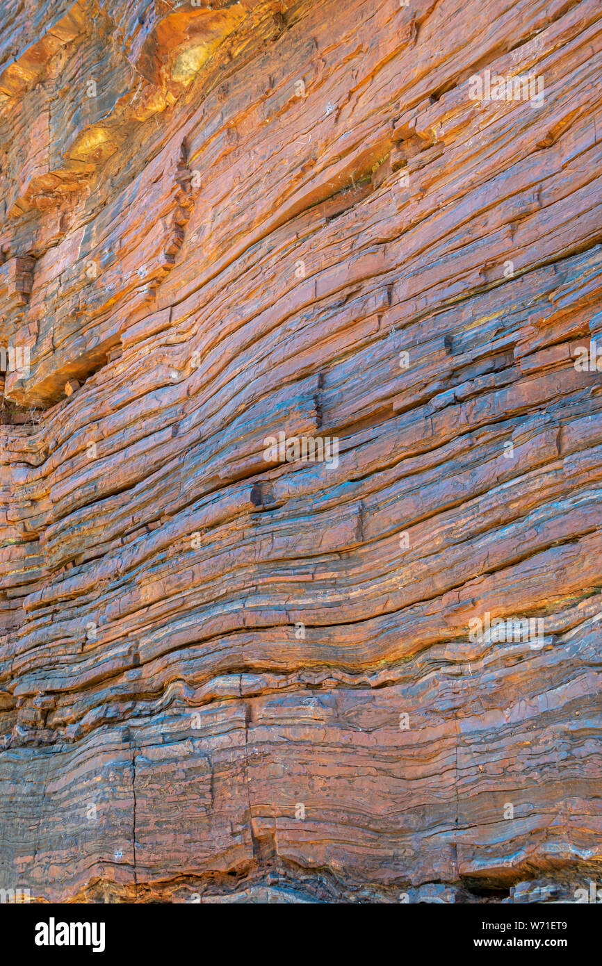 Layers of natural asbestos shining blue and iron ore rich sediment ...