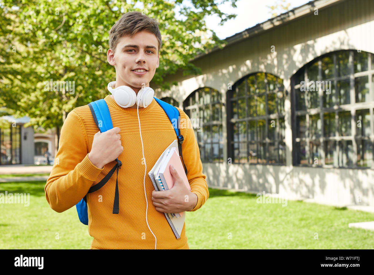 Waist up portrait of handsome college student posing outdoors in campus ...