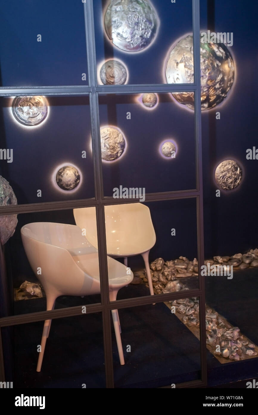 interior view of white creative chairs near wall with shiny decorative ...