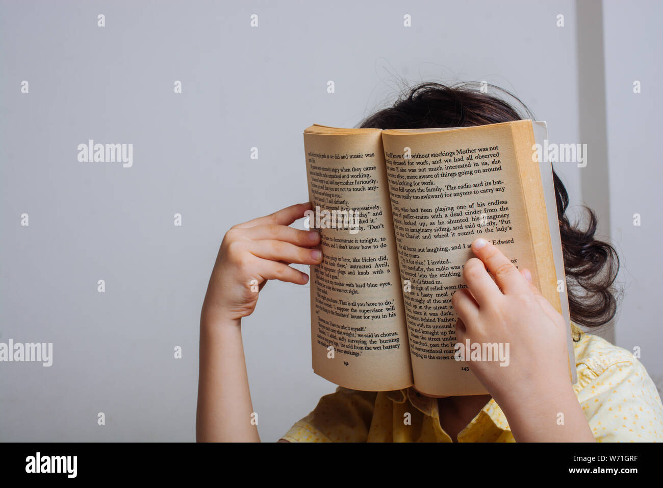 Boy covering face with book as education studying concept Stock Photo ...