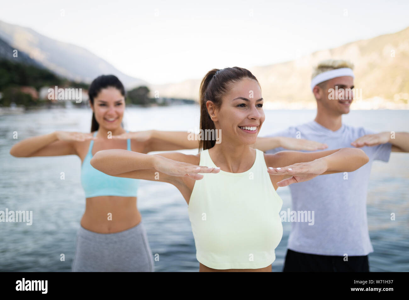 Group of happy friends or sportsmen exercising and stretching outdoor ...