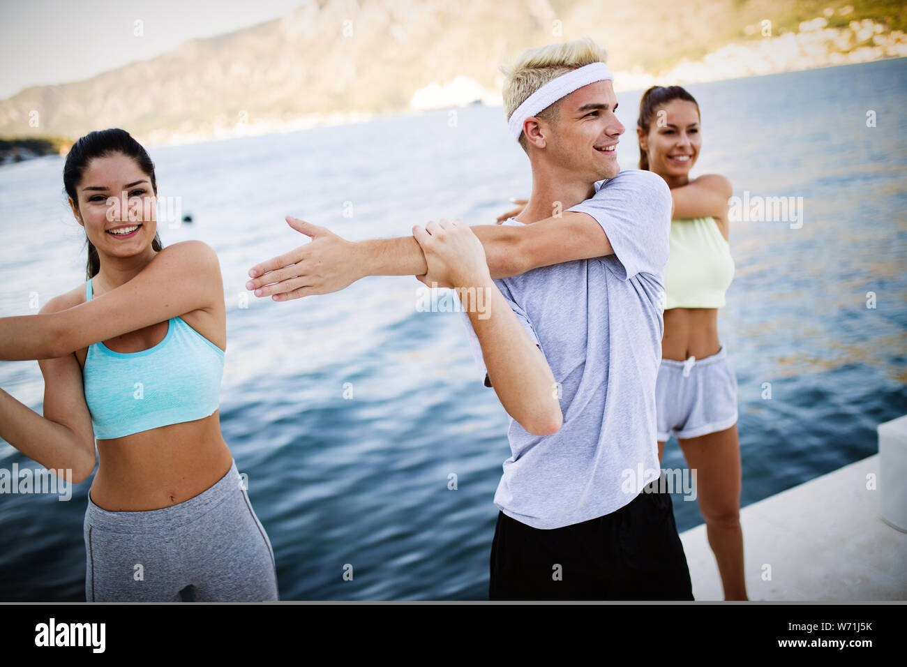 Group of happy friends or sportsmen exercising and stretching outdoor ...