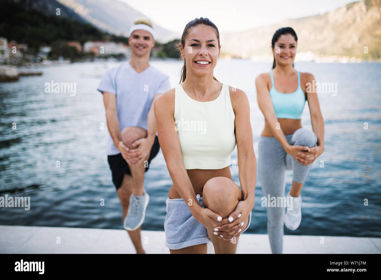 Fit group of happy people exercising outdoor. Smiling friends doing ...