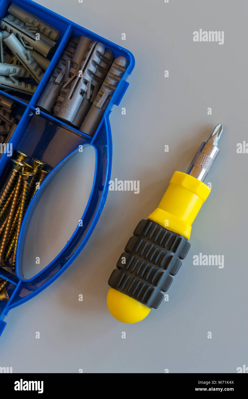 Tool box with screws, various types of parts and screwdrivers On a gray ...