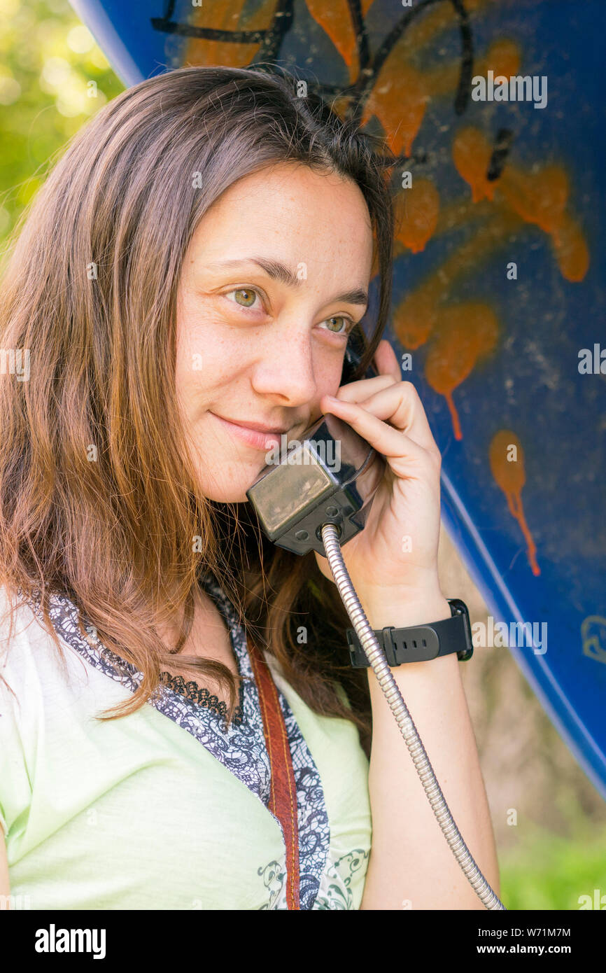 Beautiful young woman in a phone booth. The girl is talking on the ...