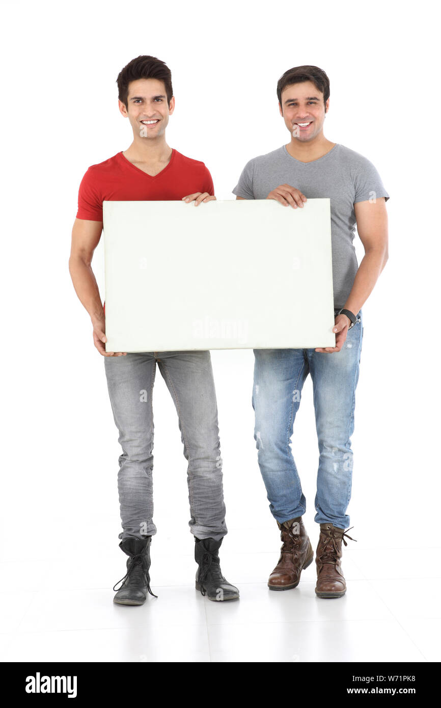 Two friends showing a placard and smiling Stock Photo - Alamy