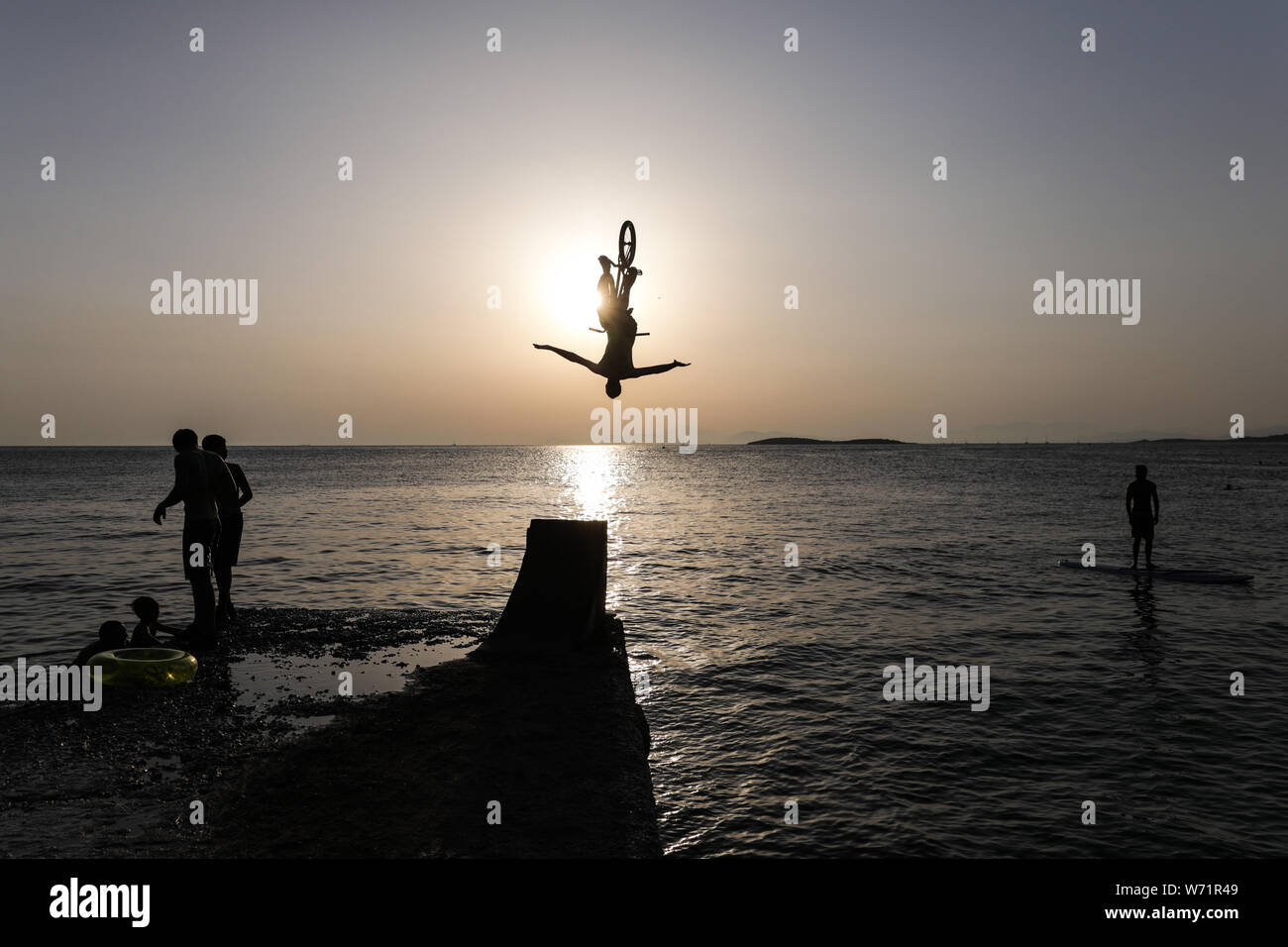 Athens, Greece. 3rd Aug, 2019. A cyclist jumps into the sea with his ...