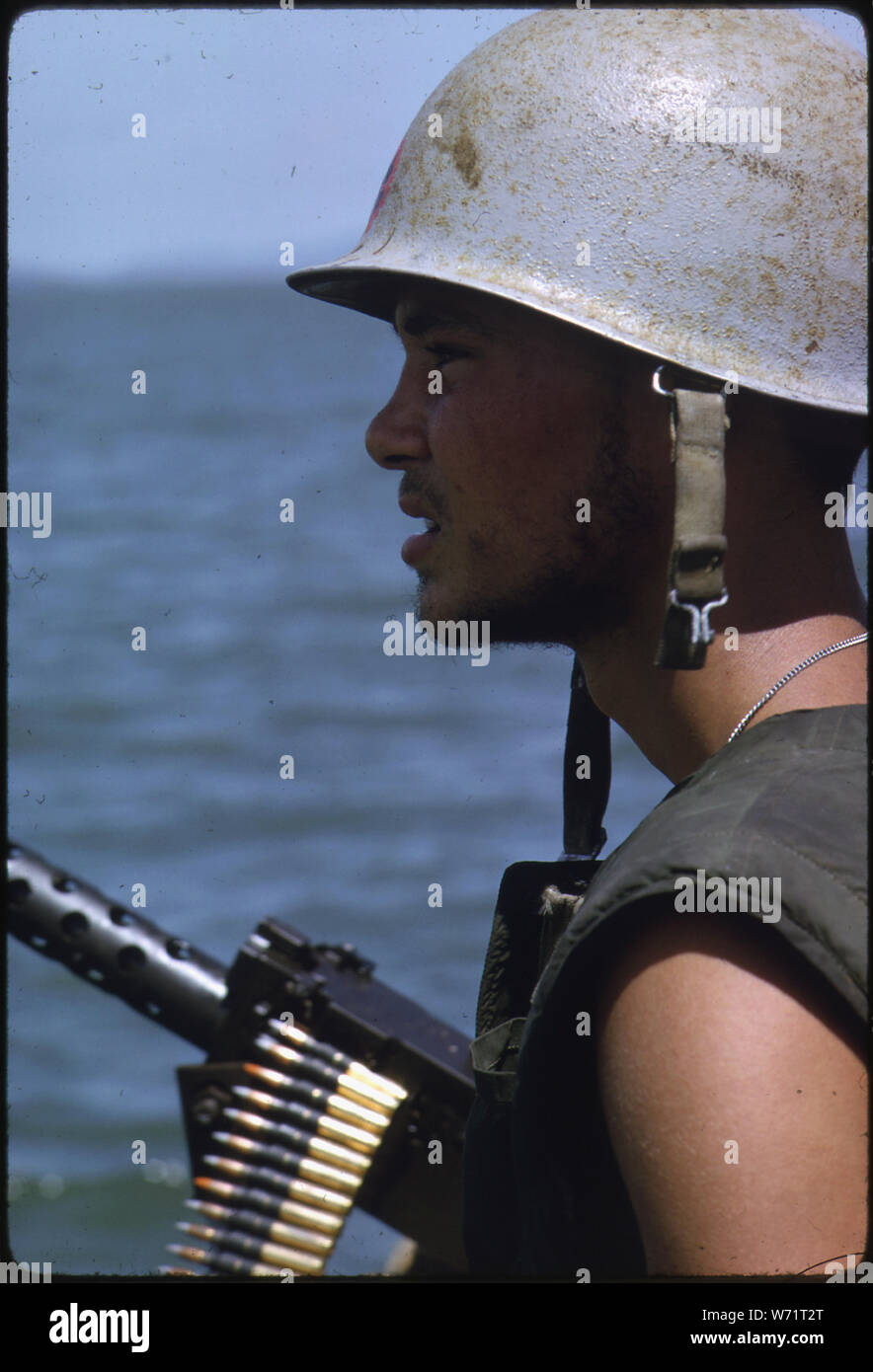 A Navy gunner mans his 50 caliber machine gun on utility boat as it ...