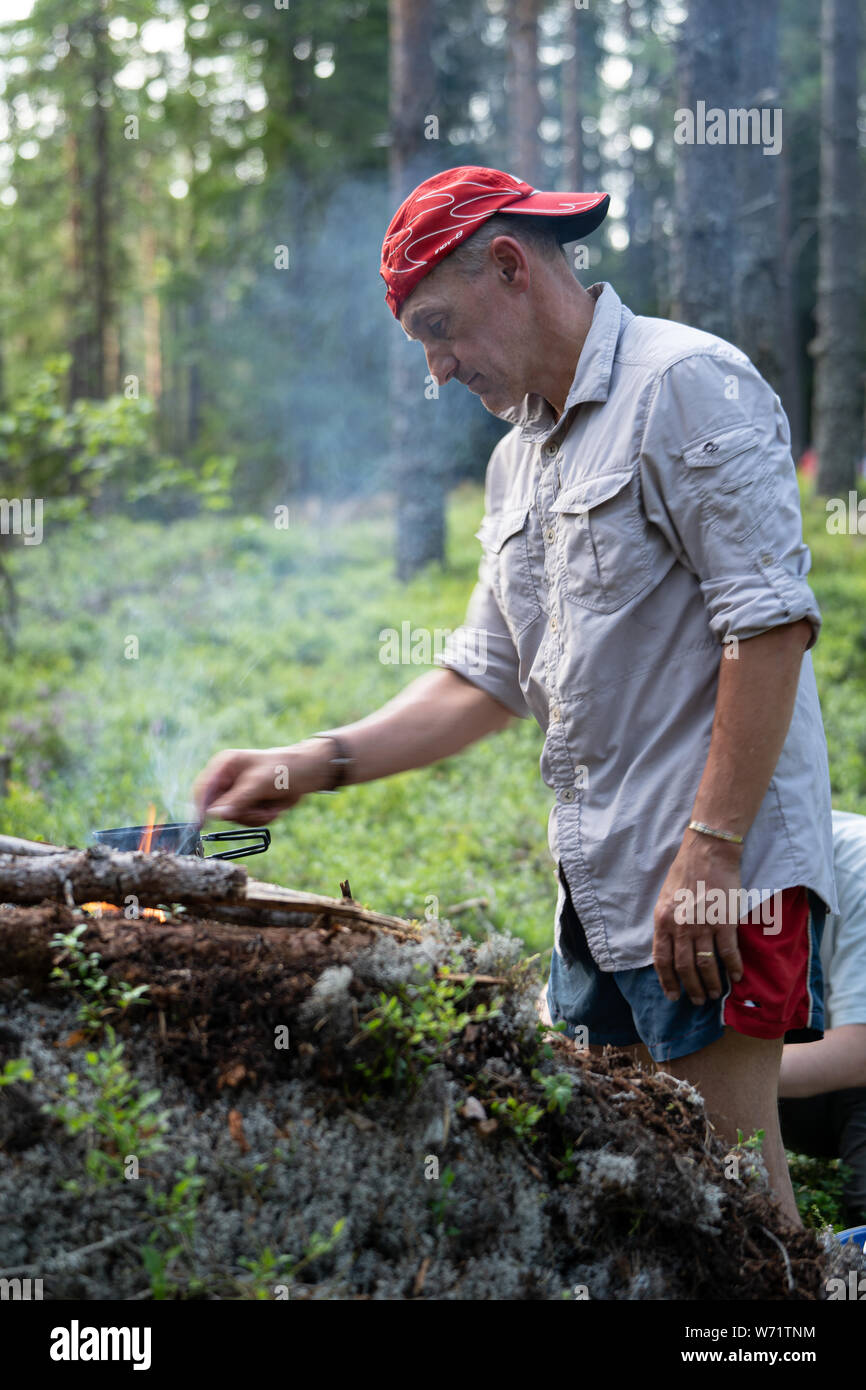 A man cooking on a fire while wild camping in a forest Stock Photo - Alamy
