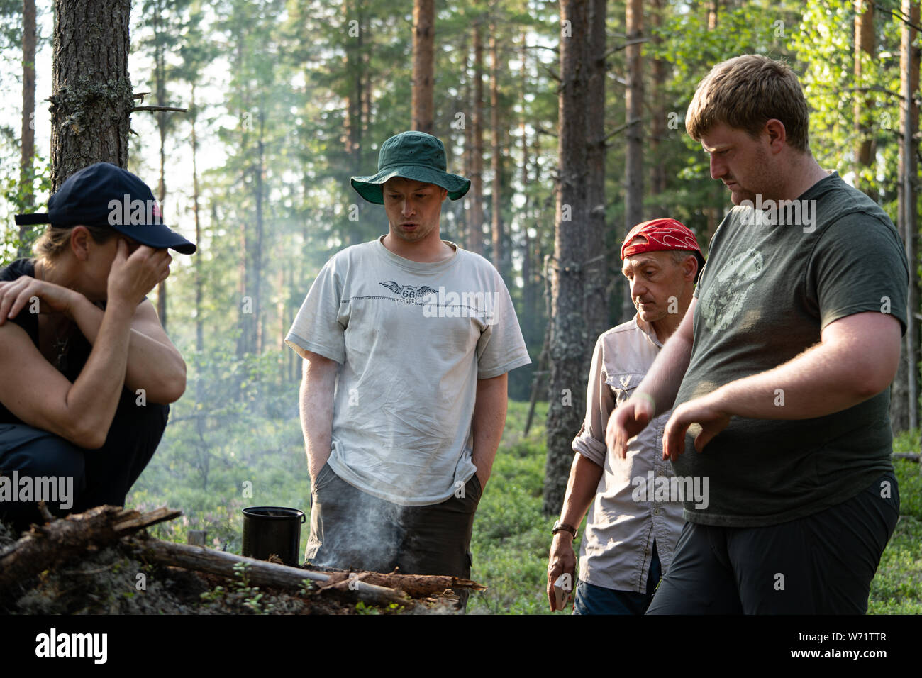 Friends wild camping in a forest, standing around a camp fire Stock ...