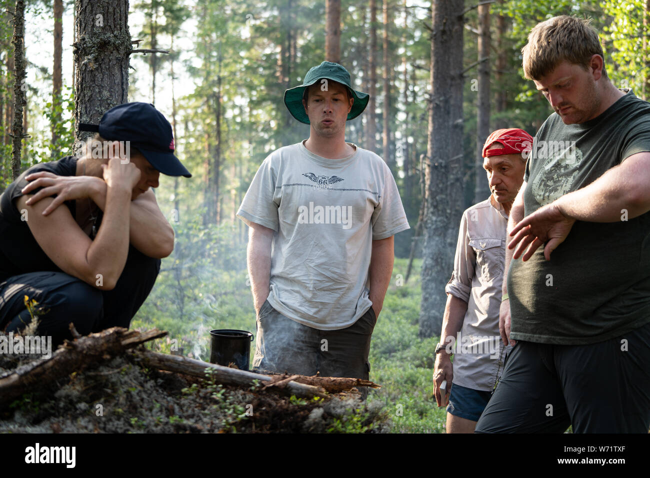 Friends wild camping in a forest, standing around a camp fire Stock ...