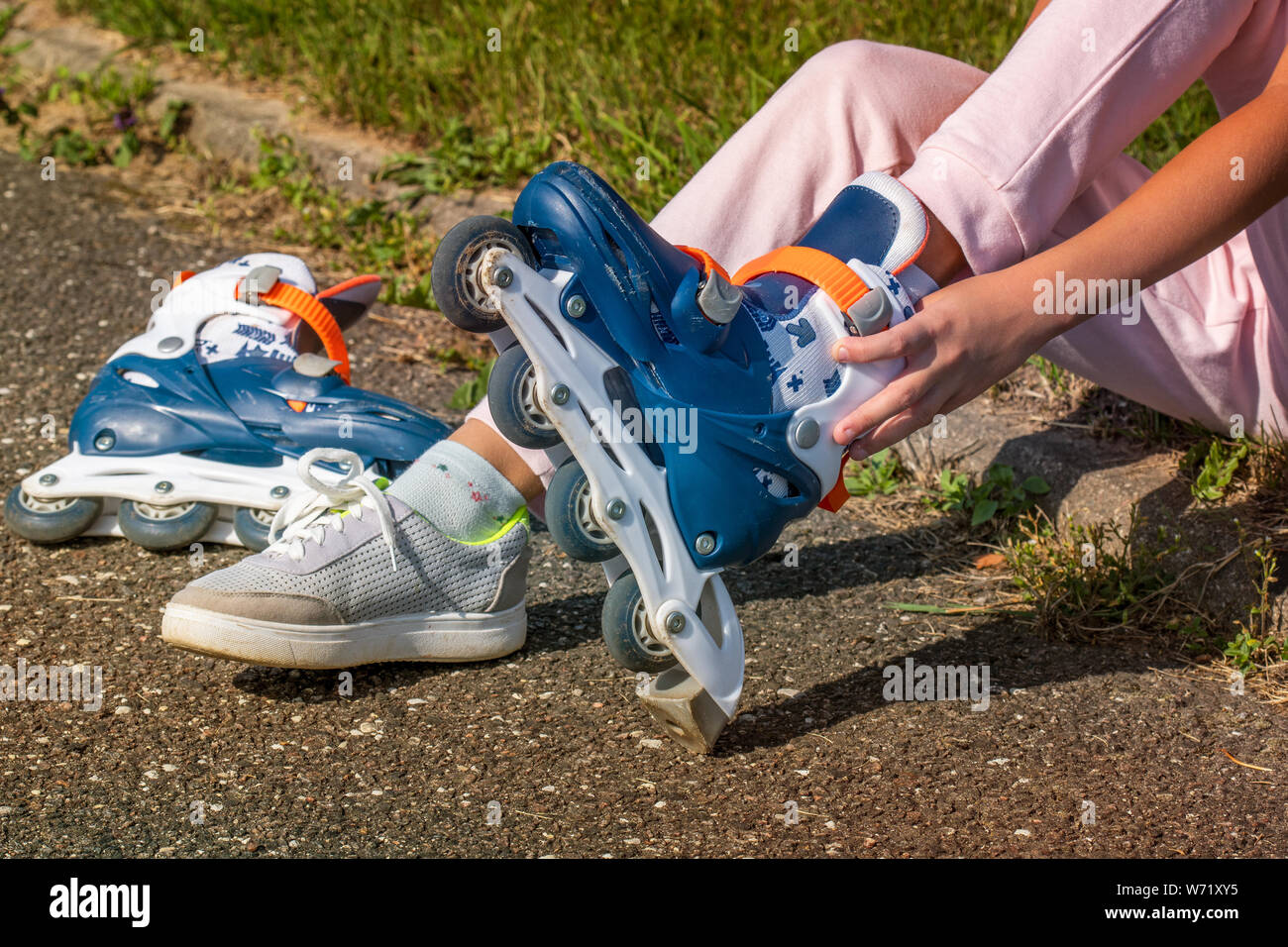 Girl sitting on green grass and putting on roller skates Stock Photo ...