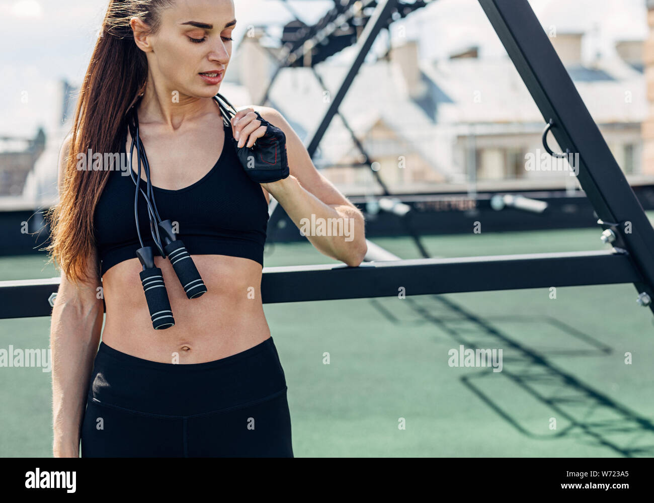Fitness woman taking a break standing with jumping rope on her neck ...