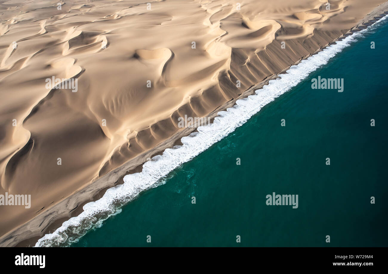 Aerial view of Skeleton coast sand dunes meeting the waves of Atlanic ...