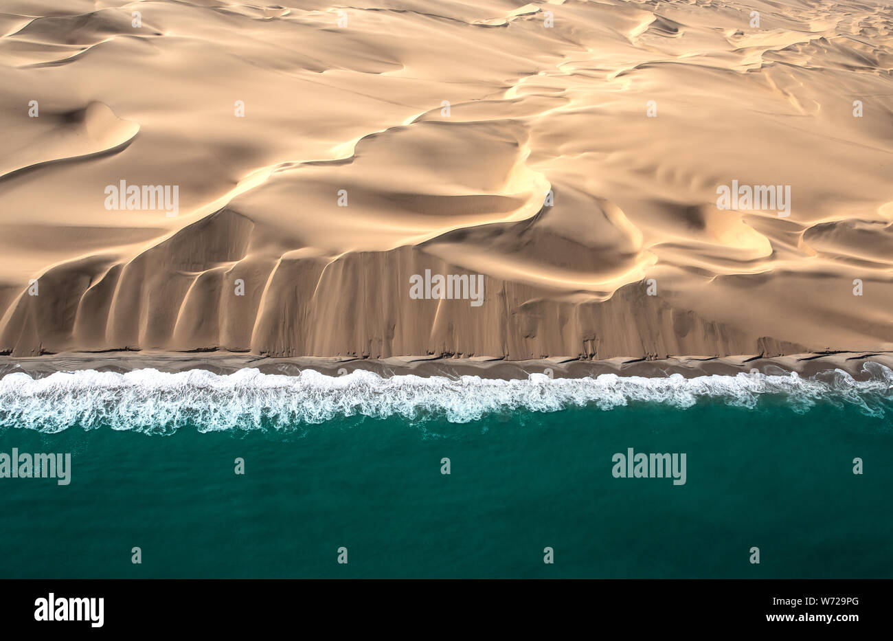 Aerial view of Skeleton coast sand dunes meeting the waves of Atlanic ...