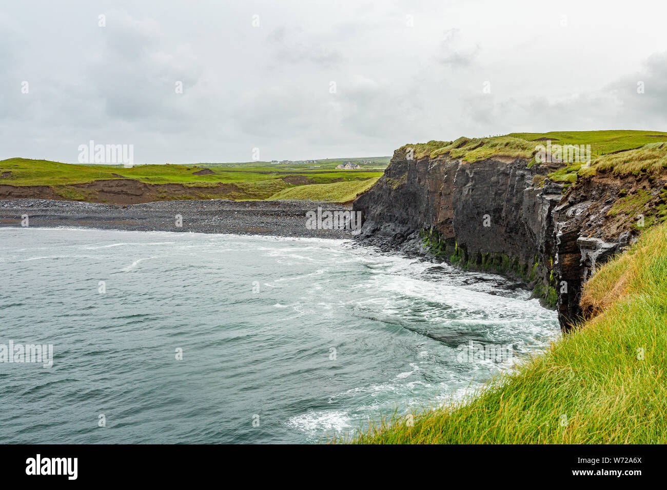 Vertical cliff wall next to a beach view from one from the hill on the ...