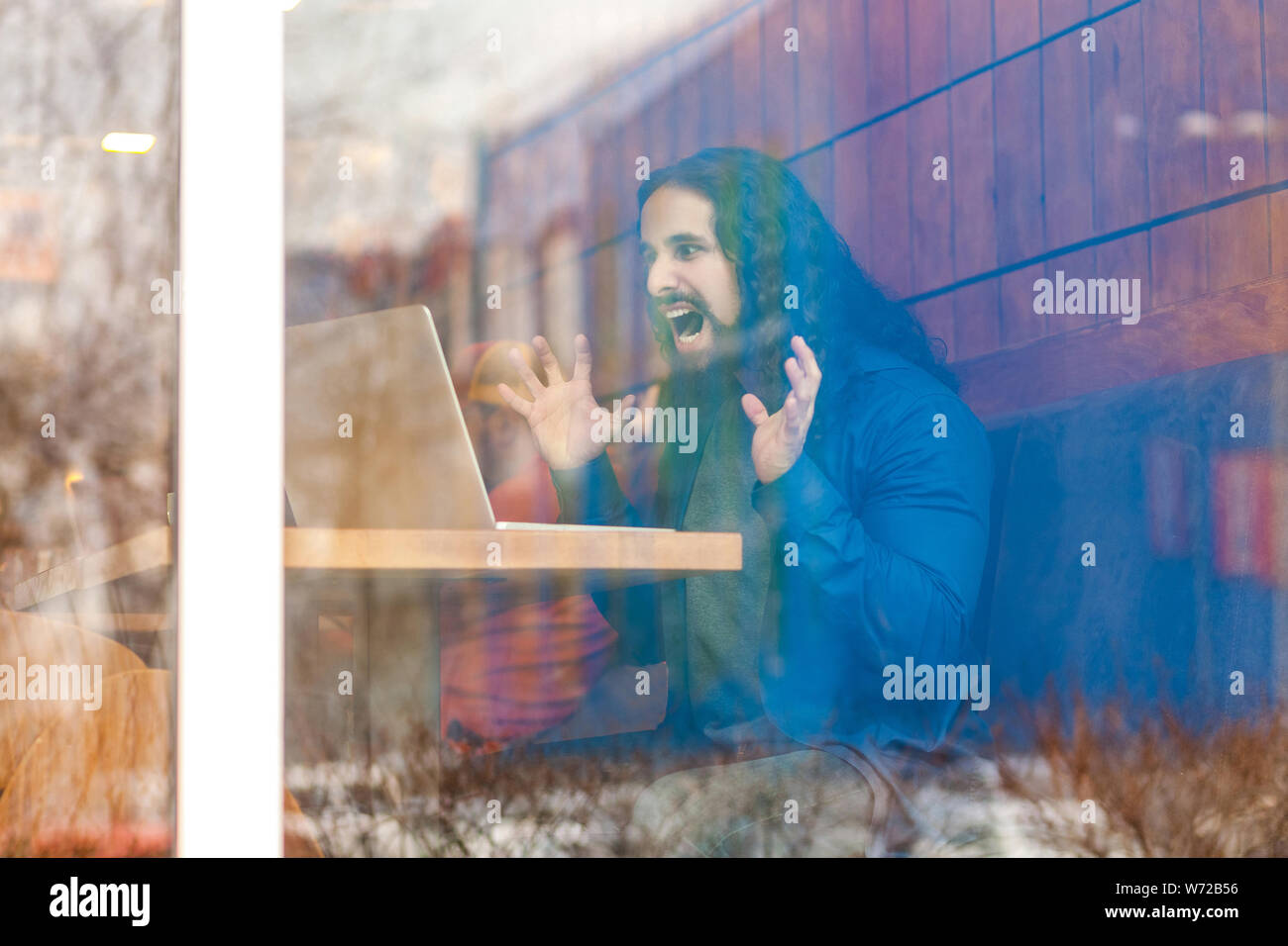 Portrait through the window of angry aggressive young adult man ...