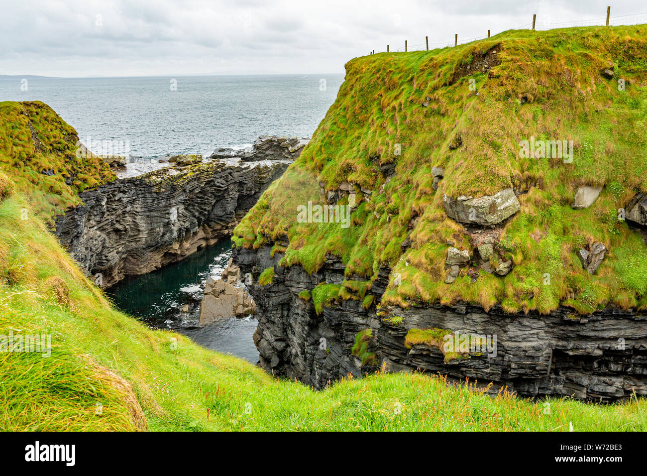 Narrow sea inlet between the hills with green grass in the coastal walk ...