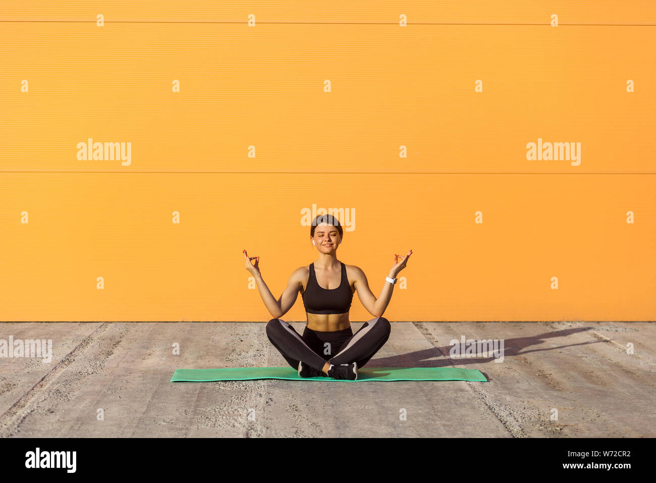 Young sporty attractive woman practicing yoga, doing ardha padmasana ...
