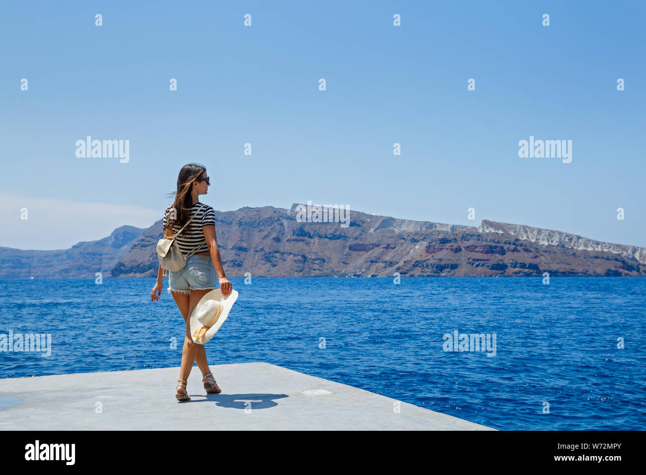 Young woman stands on the pier and looks at the sea Stock Photo - Alamy