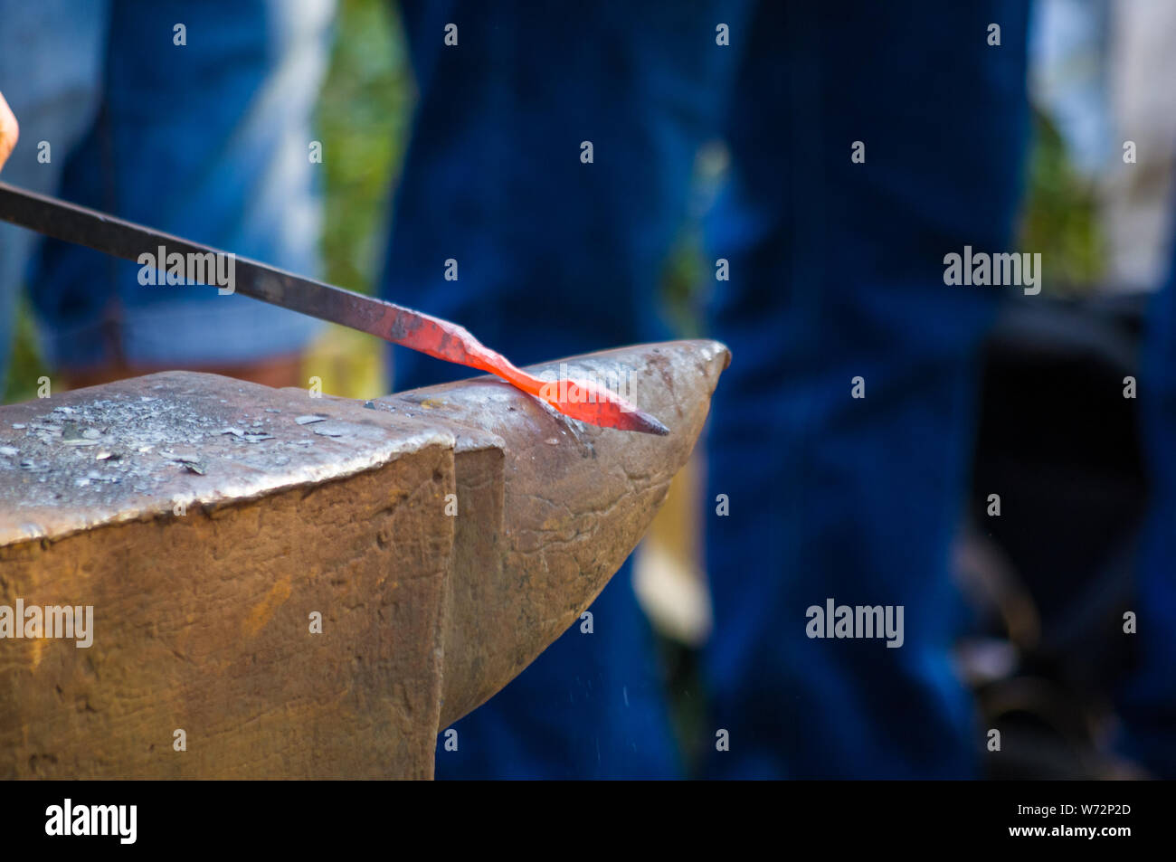 blacksmith performs the forging of hot glowing metal on the anvil ...