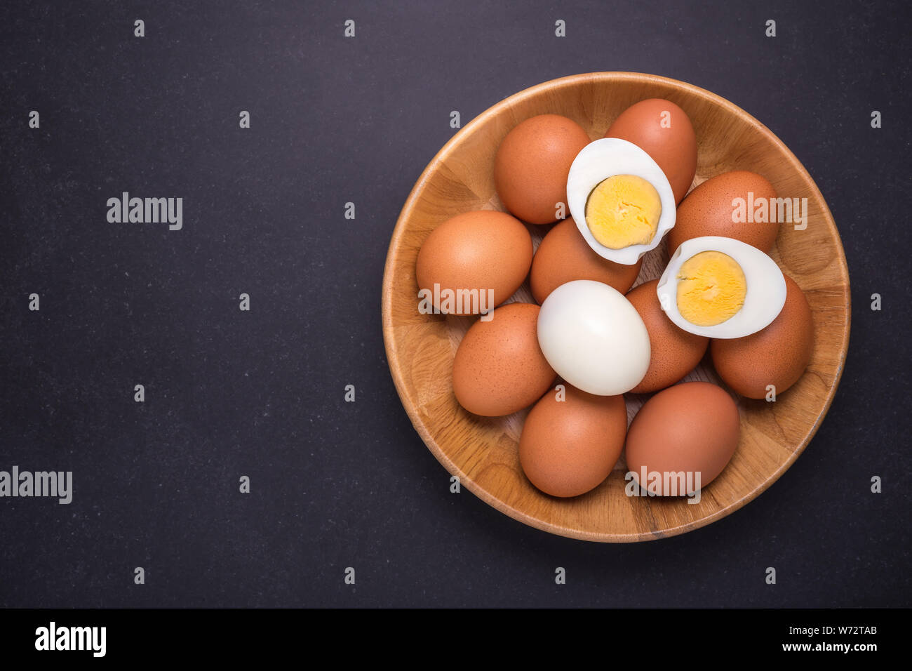 Fresh egg and boiled egg without shell. Top view on black stone ...