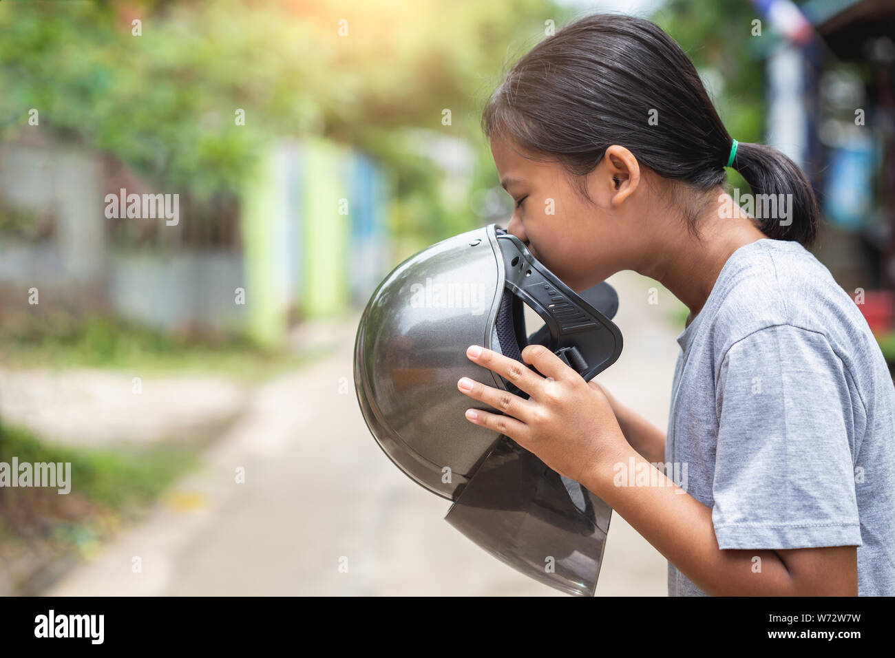 Young asian girl holding brown helmet of motorcycle and smelling. Old ...