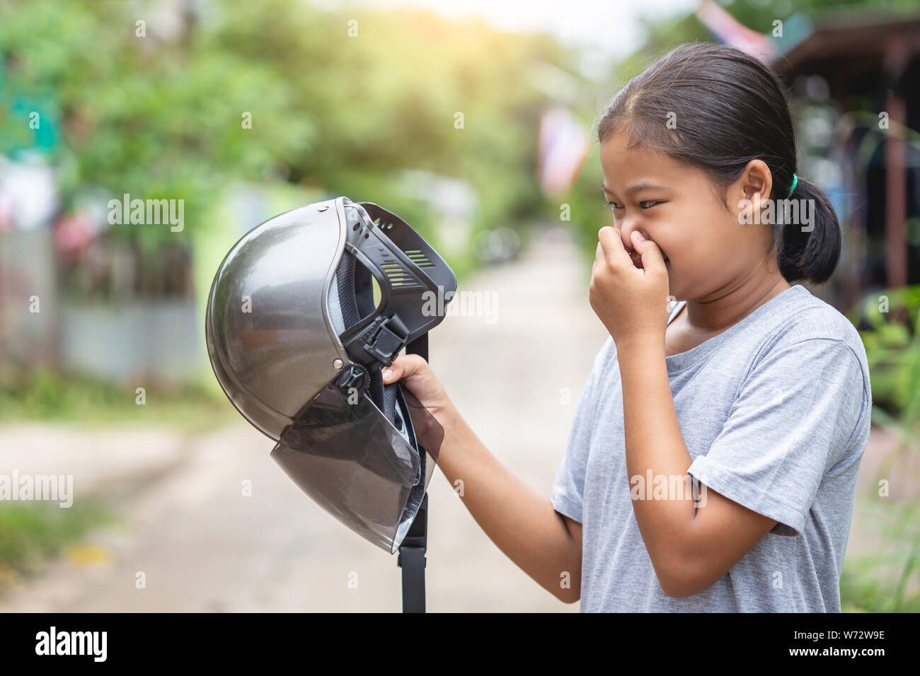 Young asian girl holding brown helmet of motorcycle and smelling. Old ...