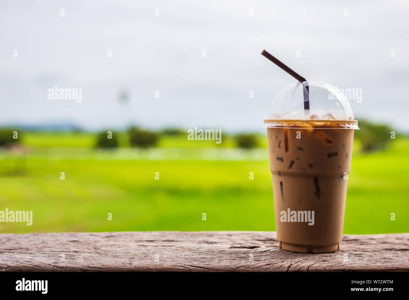 Close up iced coffee in plastic cup with drinking straw on terrace and ...