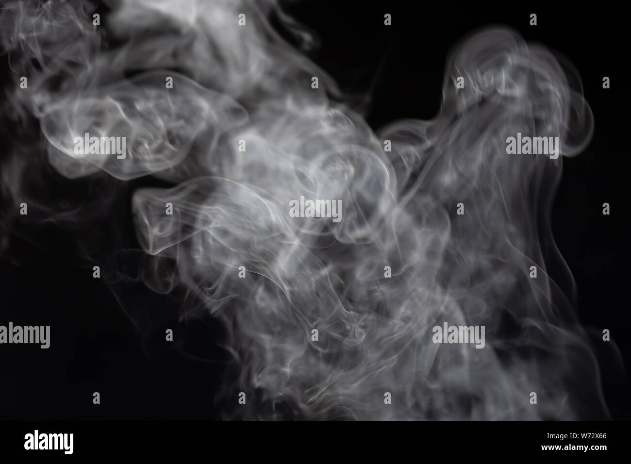 Traditional silver cooking pot with white smoke while cooking on black ...