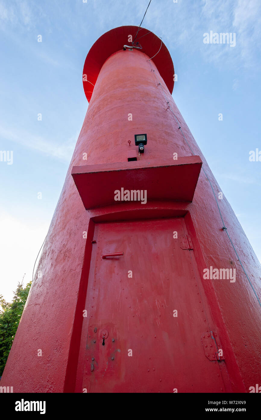 Old red lighthouse with an iron door with rivets against the sky. Shot ...
