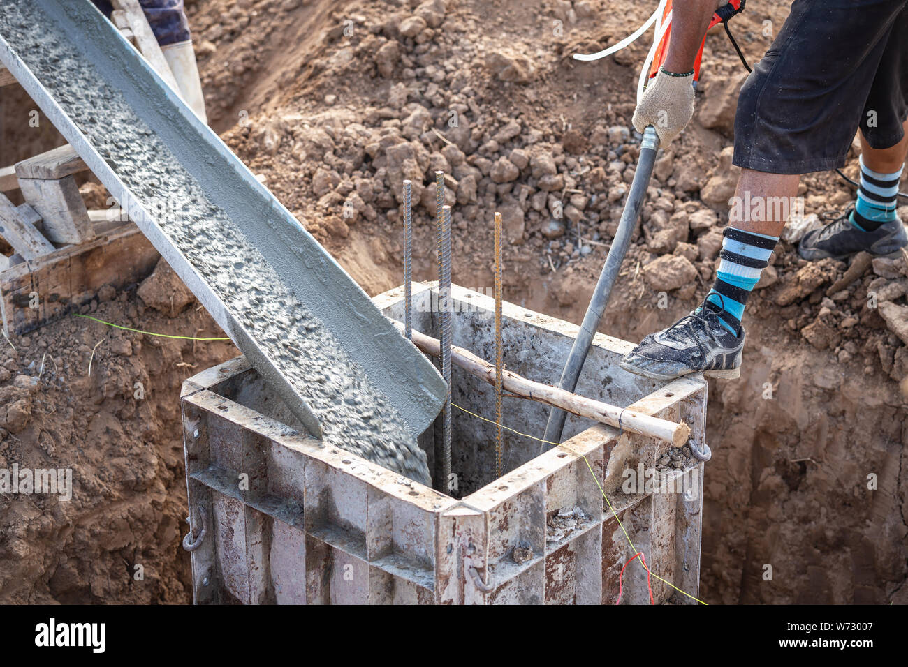 Work industrial concept : Pouring concrete into steel box for foundation pillar in process of ...