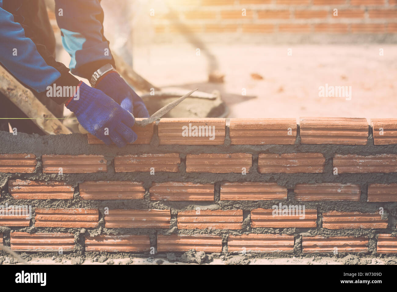 Construction worker installing bricks wall in process of house building ...
