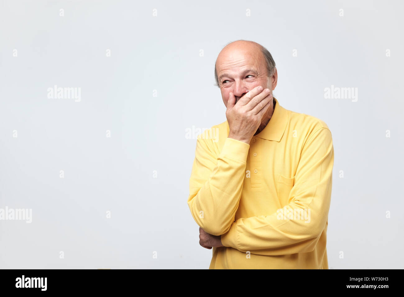 Portrait Of Mature Man Laughing And Covering His Mouth With Hand Over
