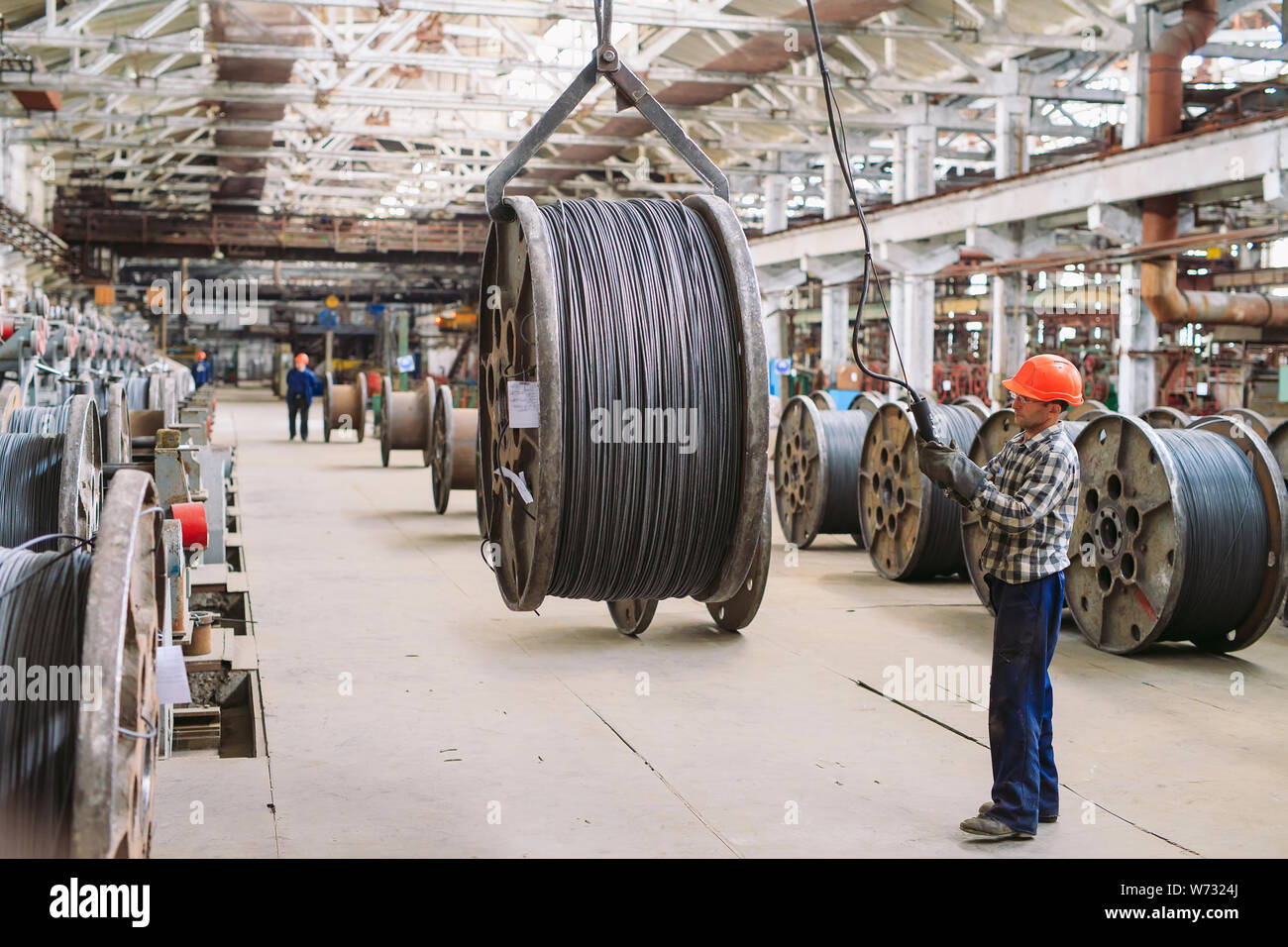 Wire rod, fittings in warehouses. worker alongside a bundle with ...
