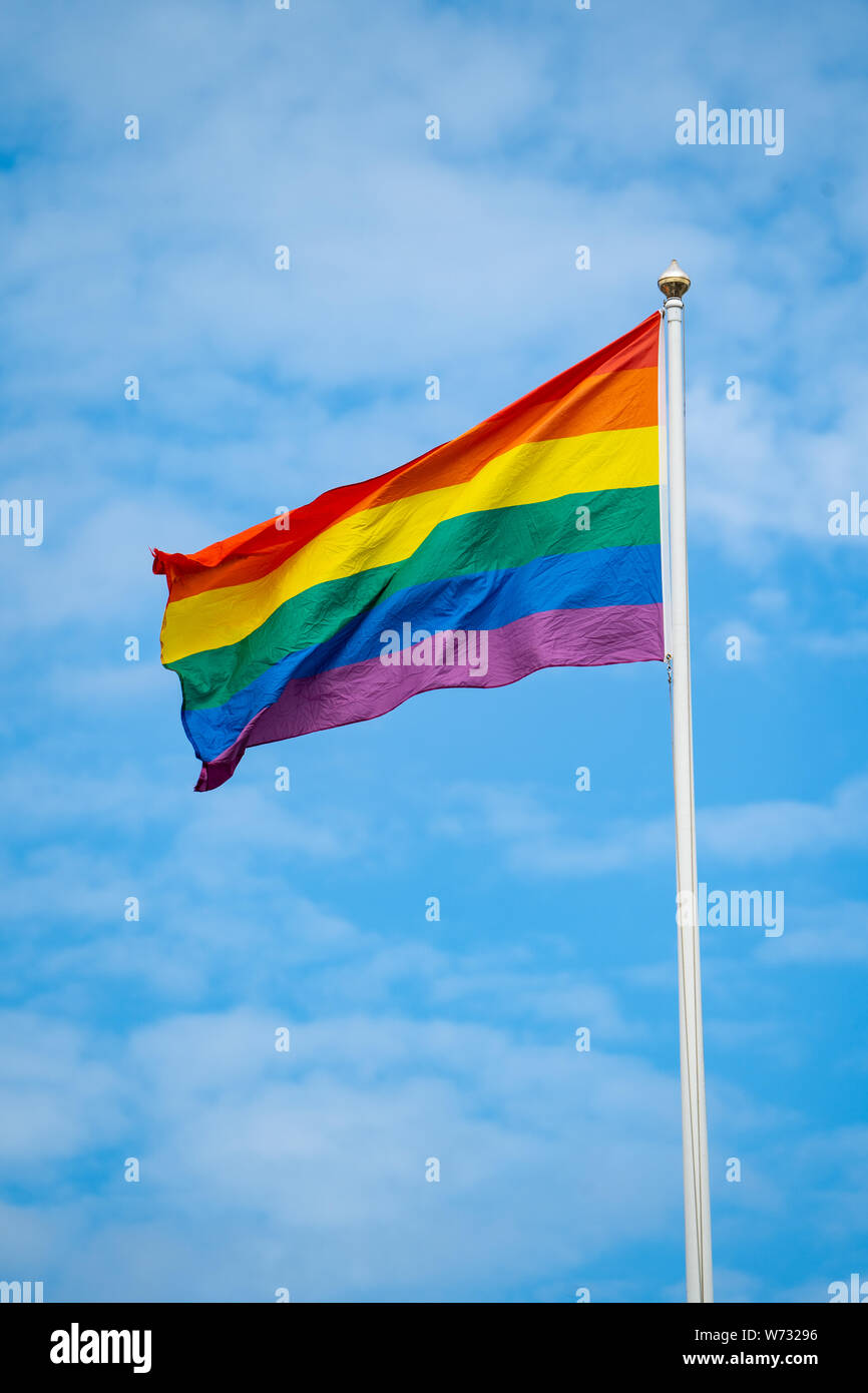 The rainbow flag against a blue sky. Gay pride flag or LGBTQ pride flag ...