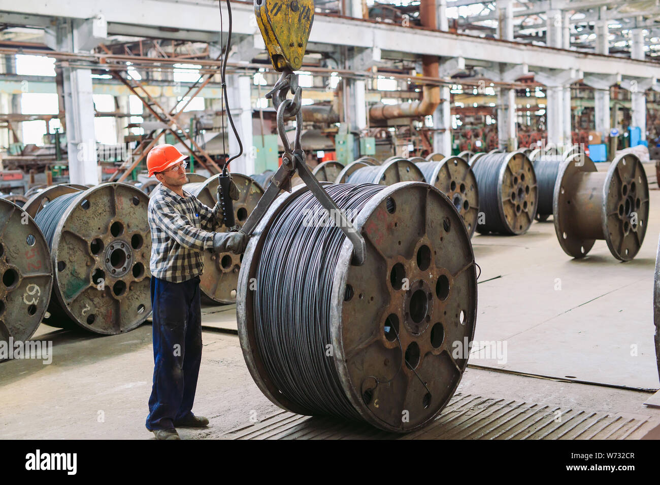Wire rod, fittings in warehouses. worker alongside a bundle with ...